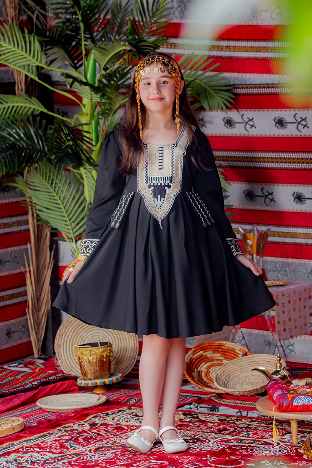 A short black traditional girls' dress decorated with gold and silver ...